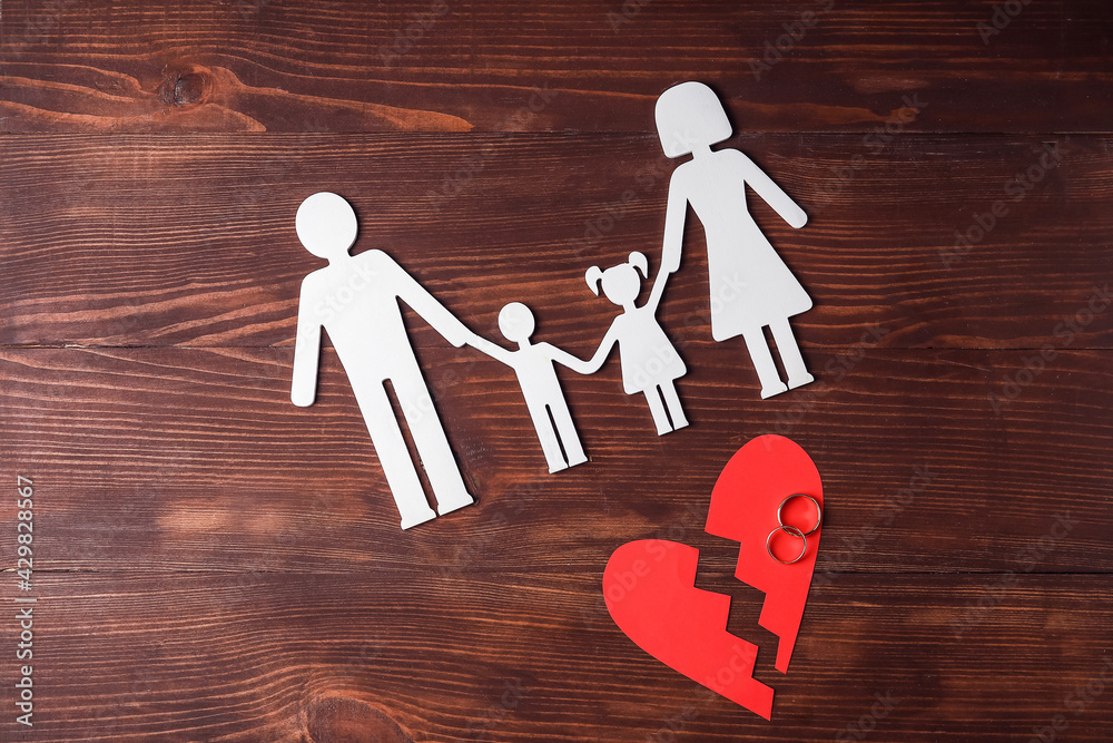 Figures of family with broken heart and rings on wooden background ...