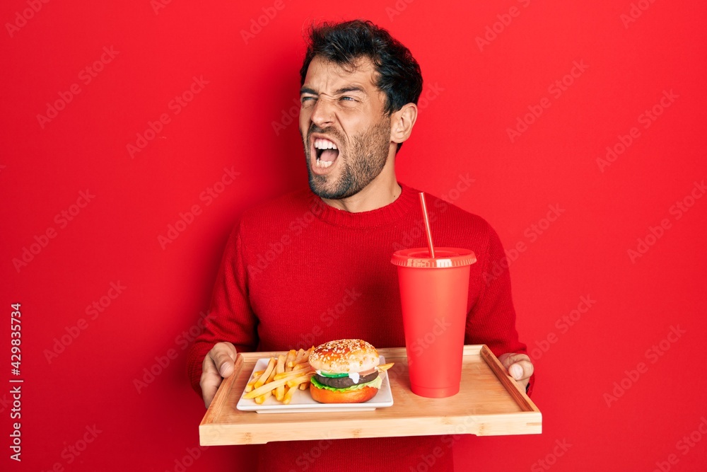 Handsome man with beard eating a tasty classic burger with fries and ...