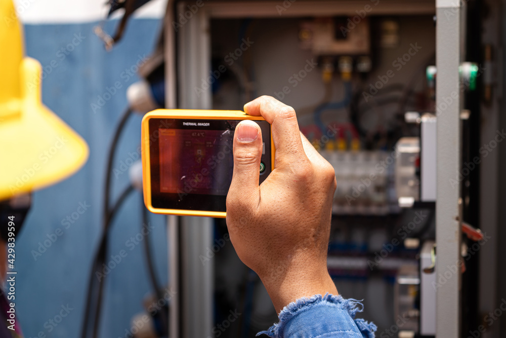 An electrician using thermal imager camera device to scanning heat and ...