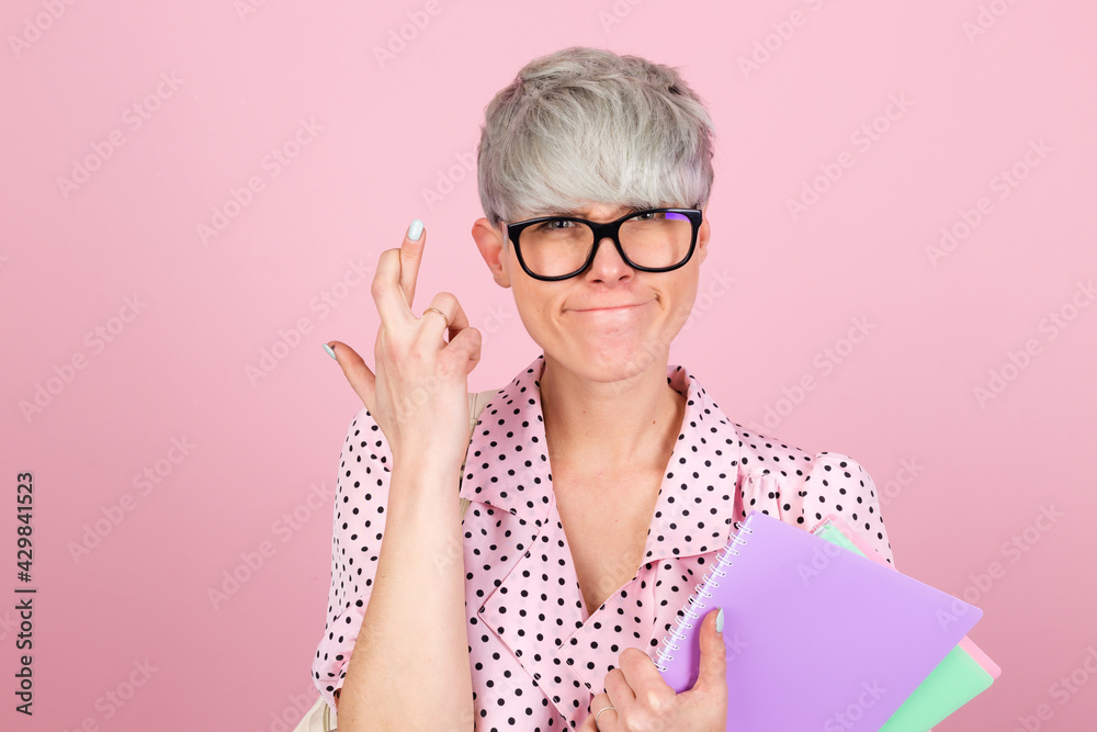 Stylish woman in dress and glasses on pink background with notebooks ...