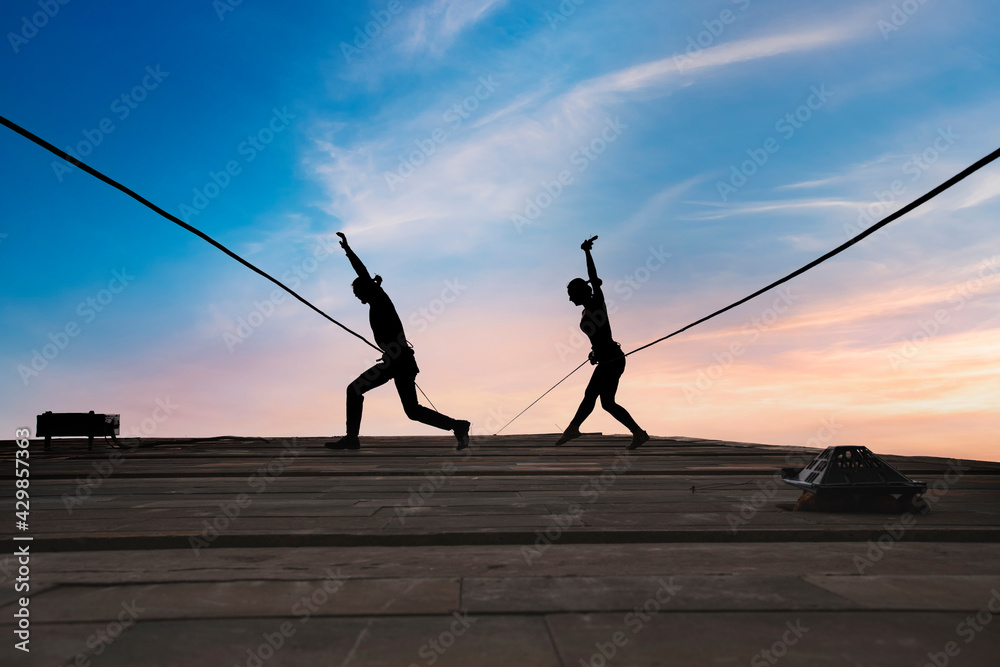 Two person silhouettes, dancing in the air, tied by the ropes on the ...