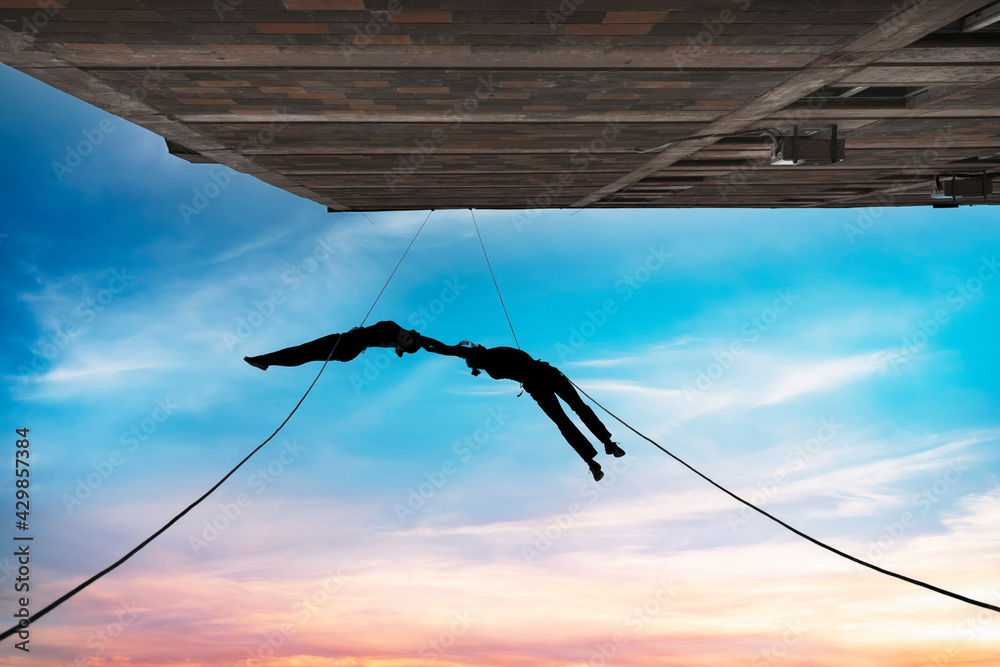 Two person silhouettes, dancing in the air, tied by the ropes on the ...