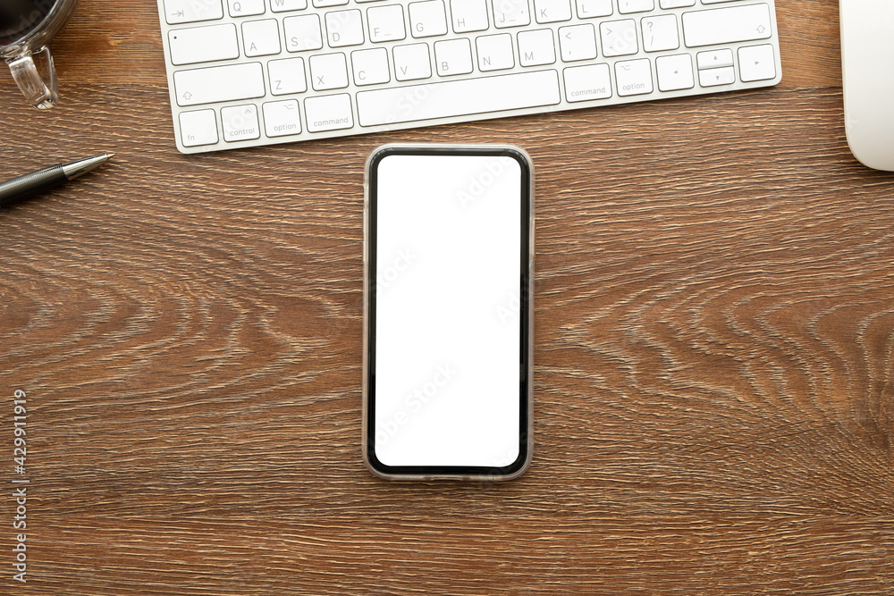 Smartphone with blank mockup screen is on top of wood office desk table ...