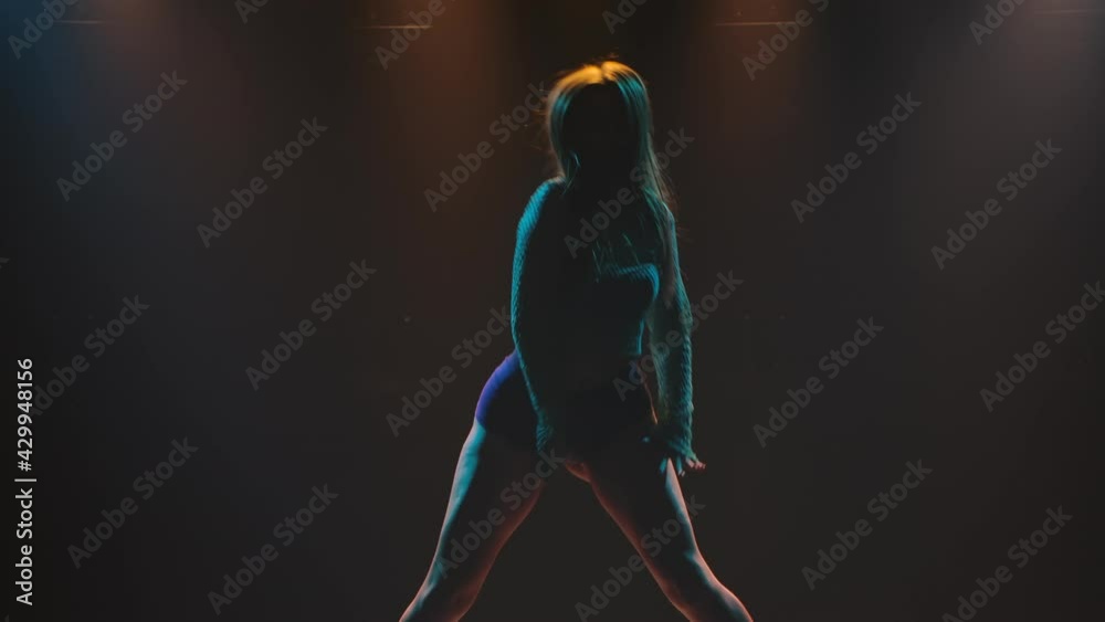 Seductive twerk dance performed by an alluring dancer in short shorts. Silhouette of a young ...