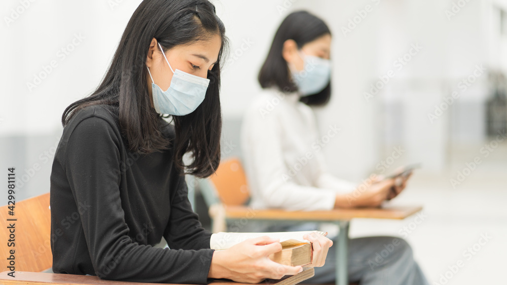 Female teenager college students wearing a face mask and keep distance ...