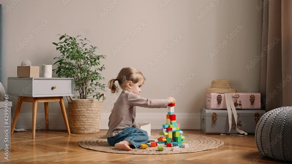 4k little girl sitting on the floor and playing with colorful blocks ...