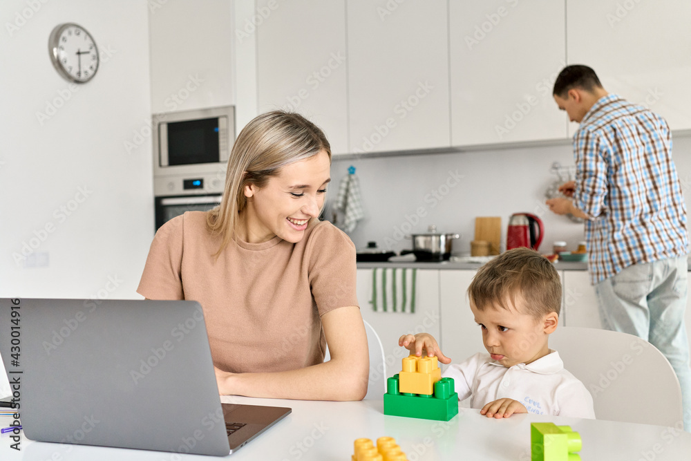 Young happy mother working from home office using laptop computer ...