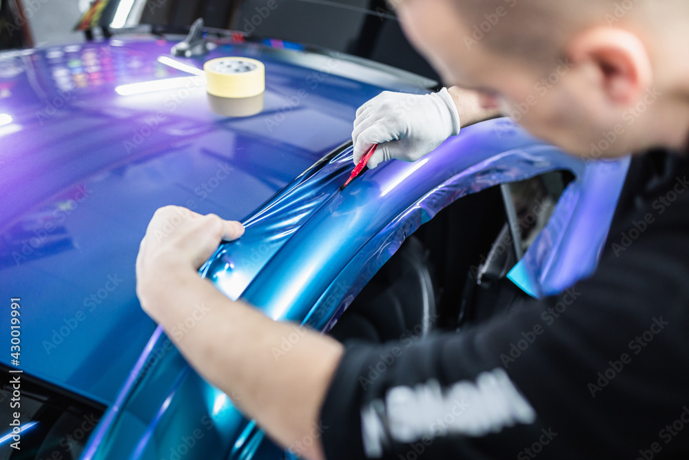 Car wrapping specialist putting vinyl foil or film on car. Selective ...
