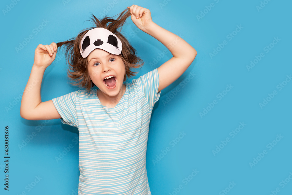 Spoiled little girl in sleeping mask, tearing her hair isolated on blue ...