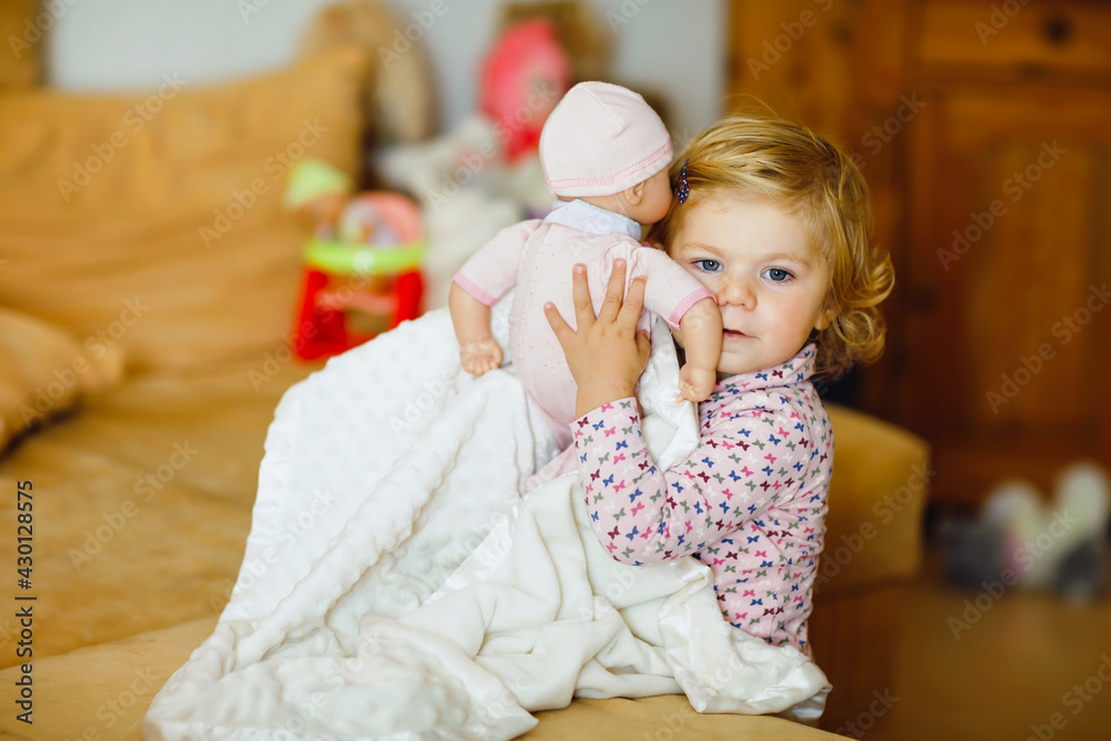 Adorable cute little toddler girl playing with doll. Happy healthy baby ...