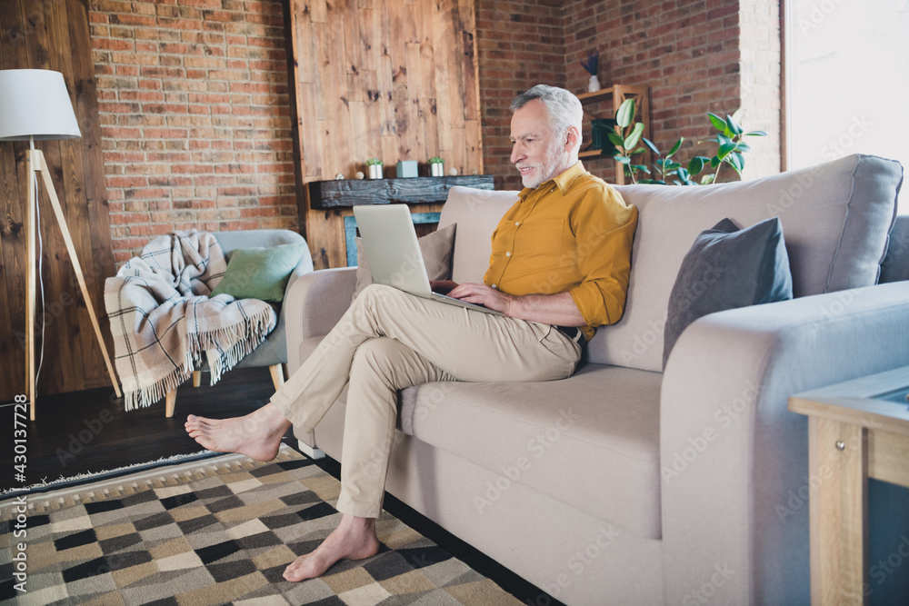 Full size profile photo of positive aged person sit on couch hold use ...