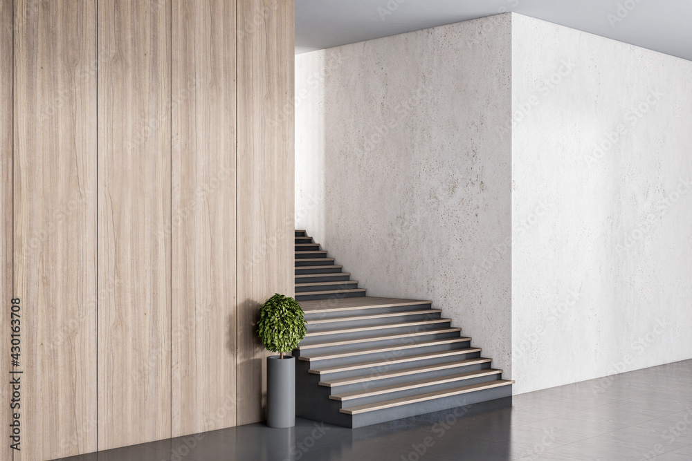 Black wooden stairs between concrete and wooden walls in spacious hall ...
