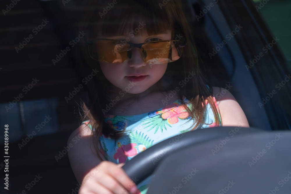 Dangers and risks of underage driving. Portrait of little child girl ...