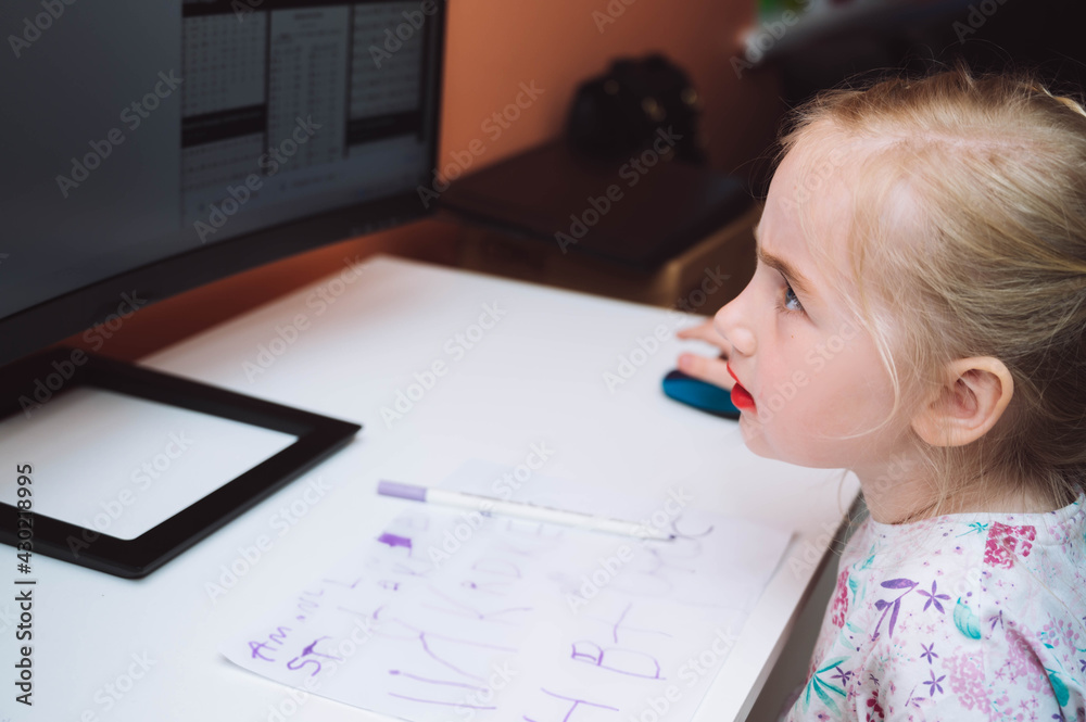 Foto de Little preschool girl looking at the computer screen, education ...