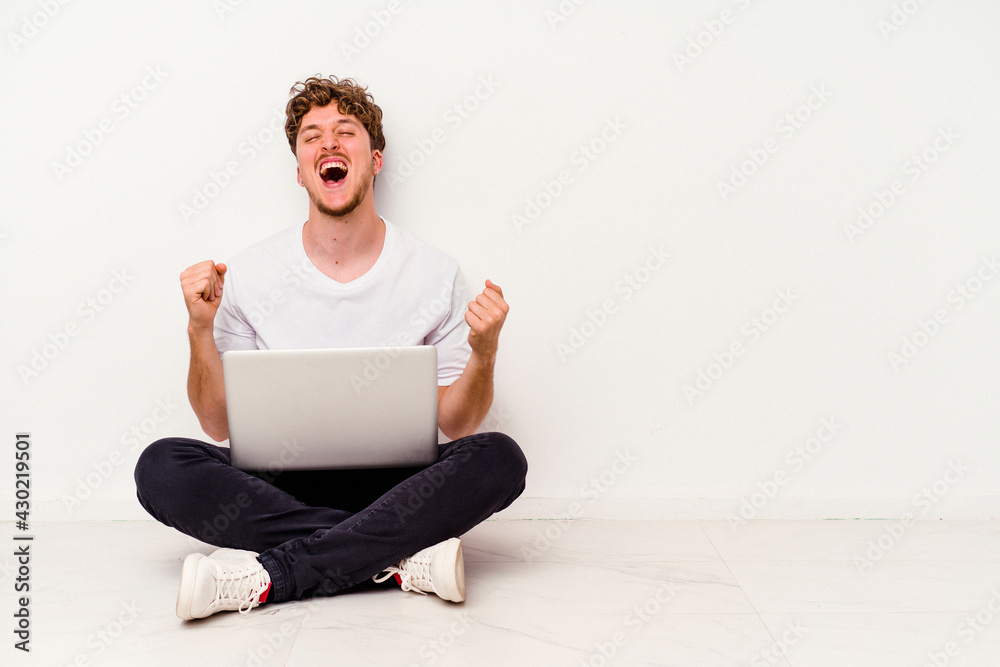 Young caucasian man sitting on the floor holding on laptop isolated on ...