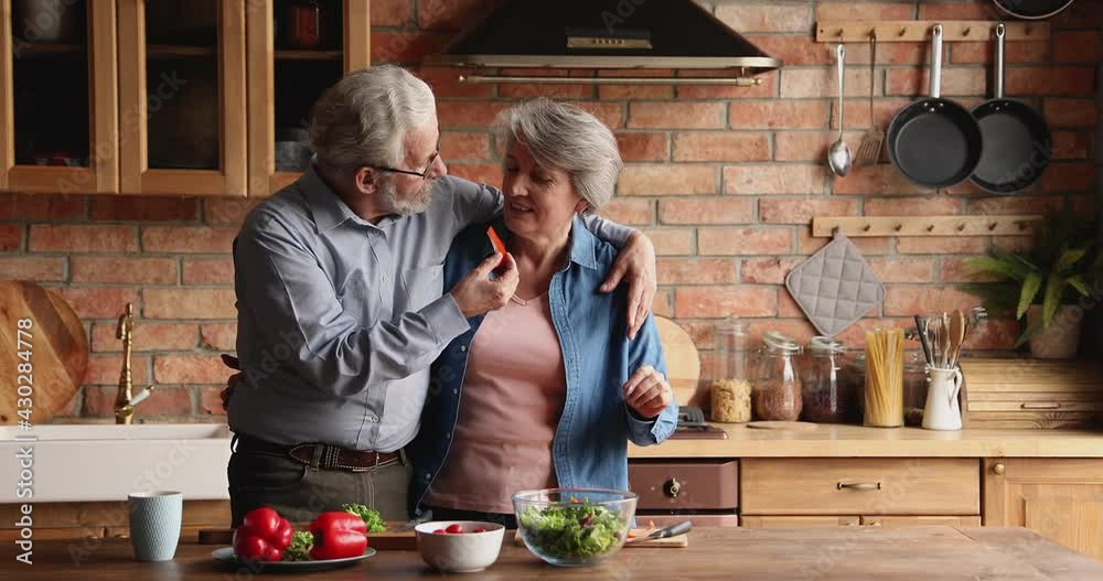 Loving affectionate mature older married couple cuddling, eating ...