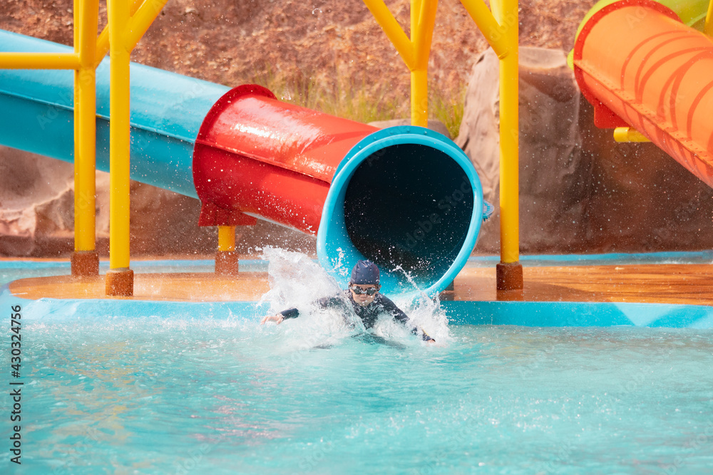 Asian child girl having fun to slide down on water slide in a water ...