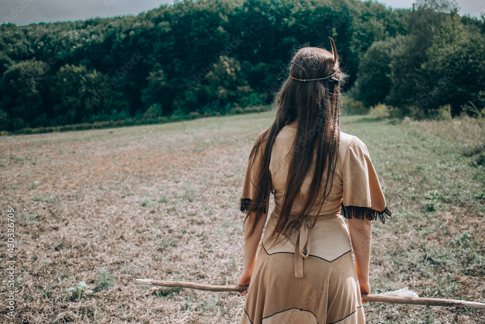 Young native american woman with a spear walking to the forest, indian ...