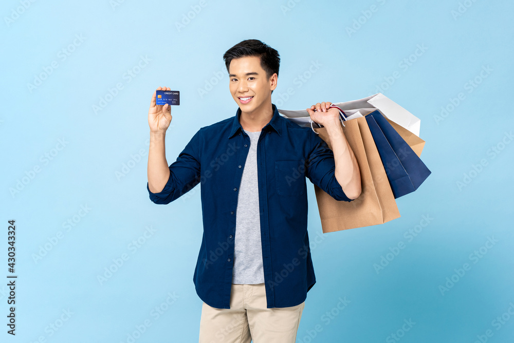 Happy smiling handsome Asian man carrying shopping bags and showing ...