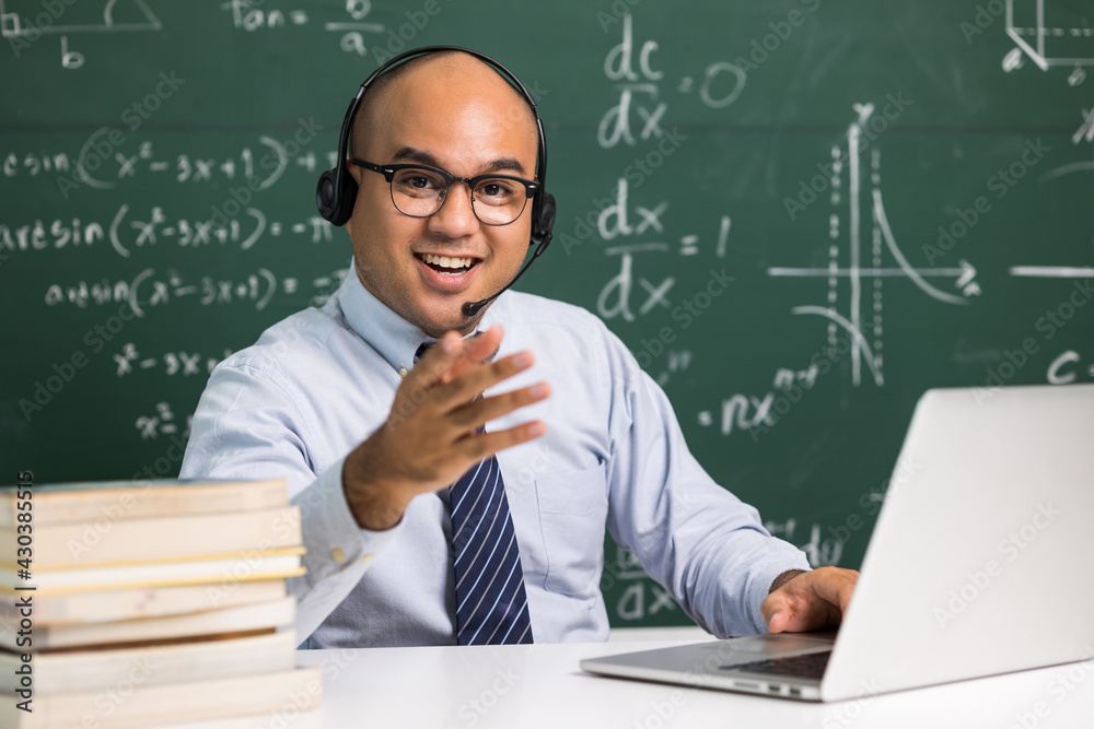 Indian young teacher man sitting wearing headset teaching online video ...