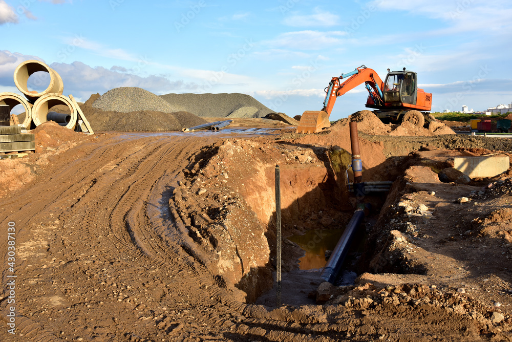 Foto de Excavator dig the trenches at a construction site. Trench for ...