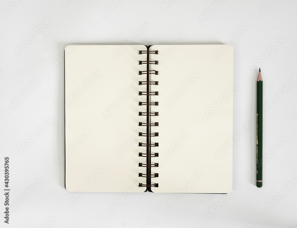 white desk with sketchbook and pencil on top of it. a notebook mockup ...