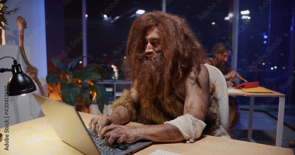 Savage bearded furry neanderthal cave human playing with laptop ...
