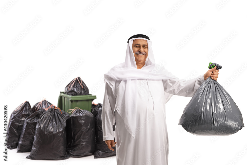 Arab man throwing a plastic waste bag in a bin with a pile of bags ...