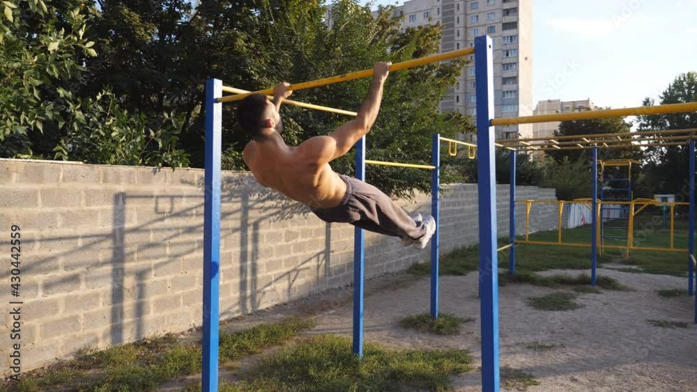 Strong sporty man showing some gymnastics stunts on horizontal bar ...