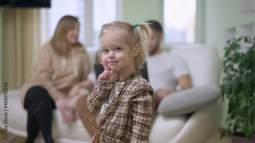 Adorable pretty Caucasian baby girl looking back at blurred family ...