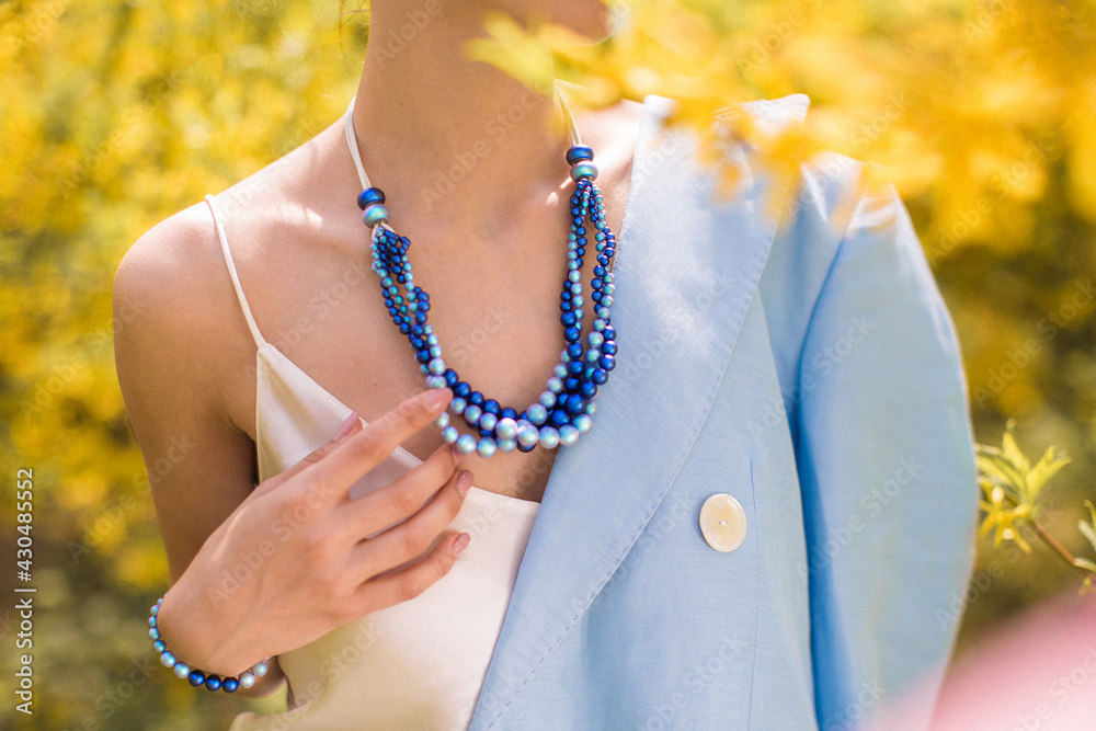 Blue pearl necklace around the neck of a young girl in a satin negligee ...