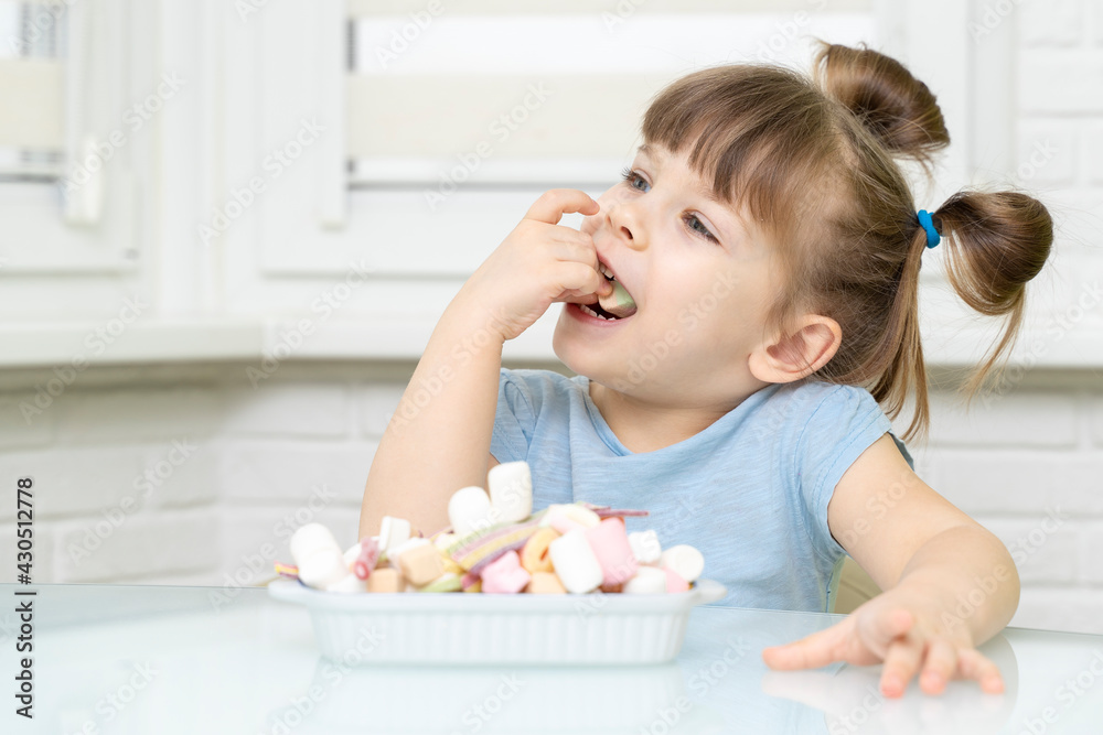 cute European female child smiling, happily eating candy, with appetite ...