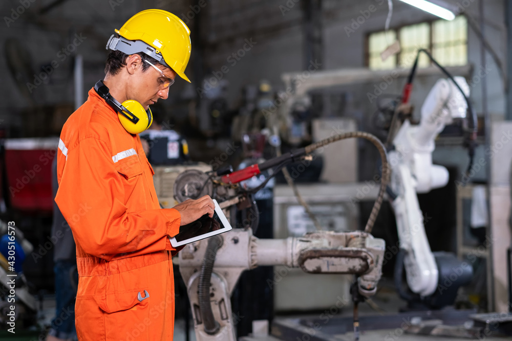 Engineer man use tablet to control welding robotic automatic arm ...