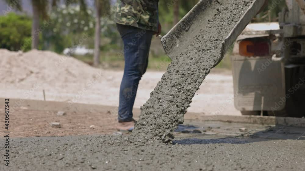 Concrete truck pours liquid concrete mix into the pump. Concrete being ...