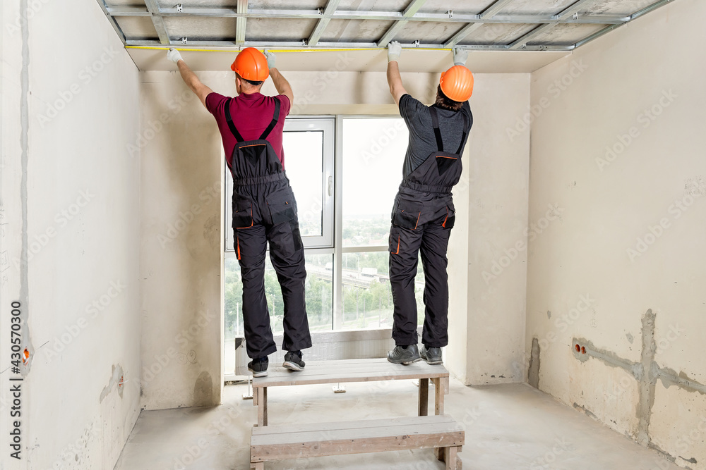 Installation of drywall. Workers are measuring. Stock Photo | Adobe Stock