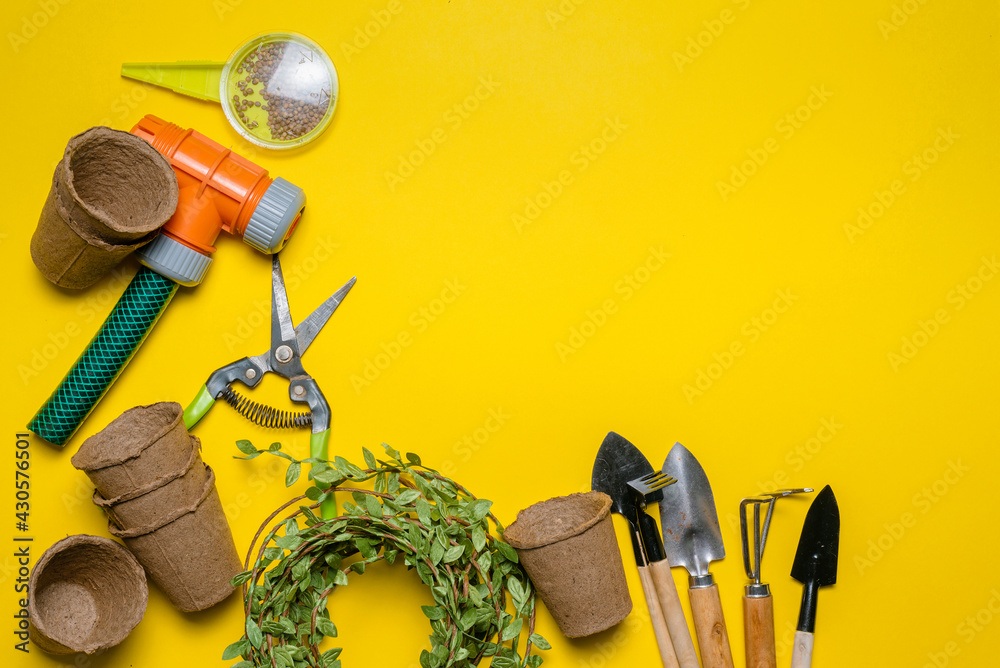 Gardening tools and flower pots with a soil on the yellow flat lay ...