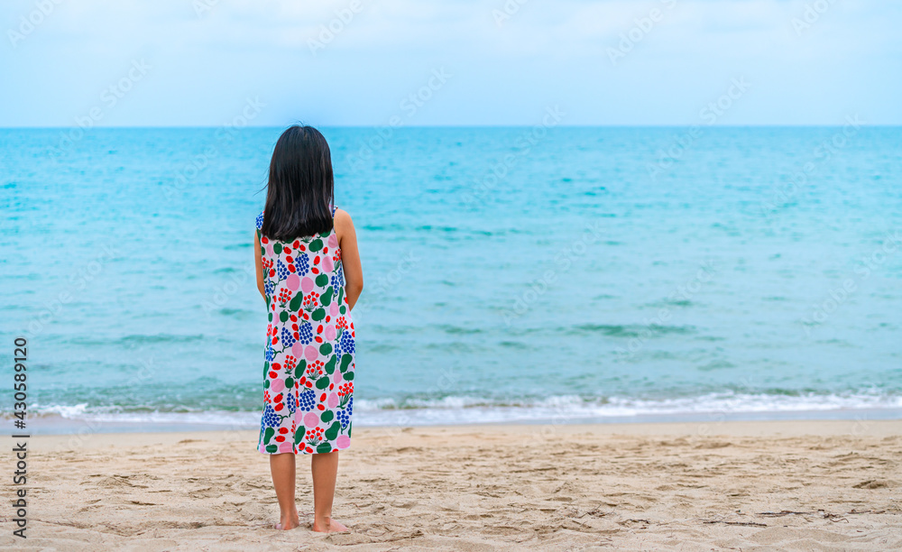 Child girl standing alone on a beautiful beach and looking to the ...