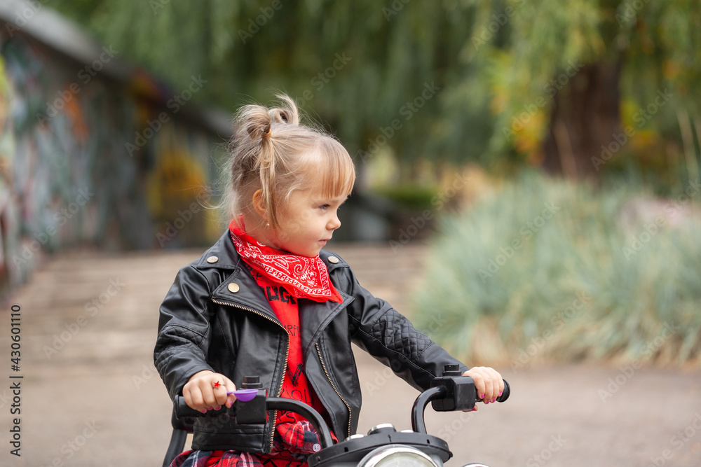 Cute cool child girl in leather jacket riding the motorbike in summer ...