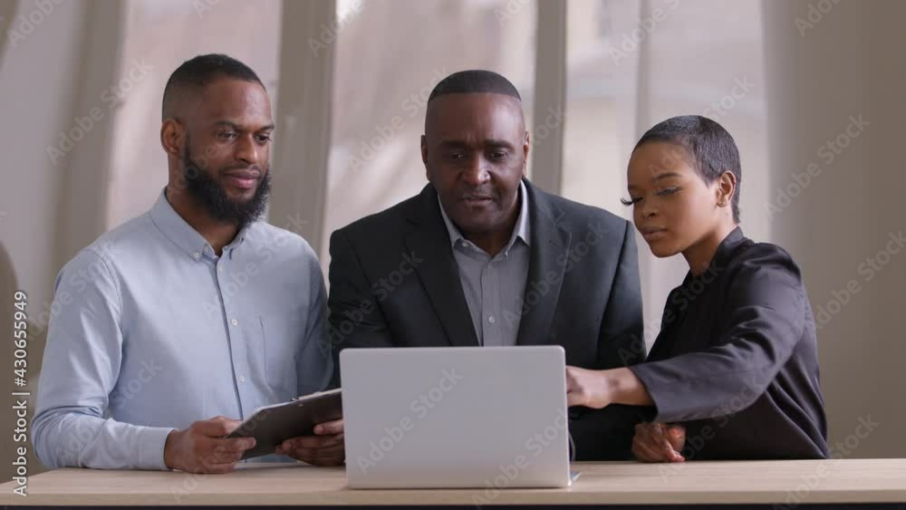 Three African business partners discussing project at office meeting ...