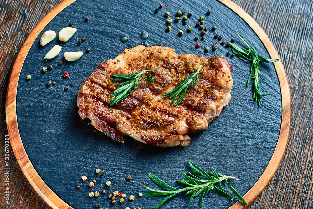 cooked pork steak with layers of lard, lies on a wood board with garlic ...