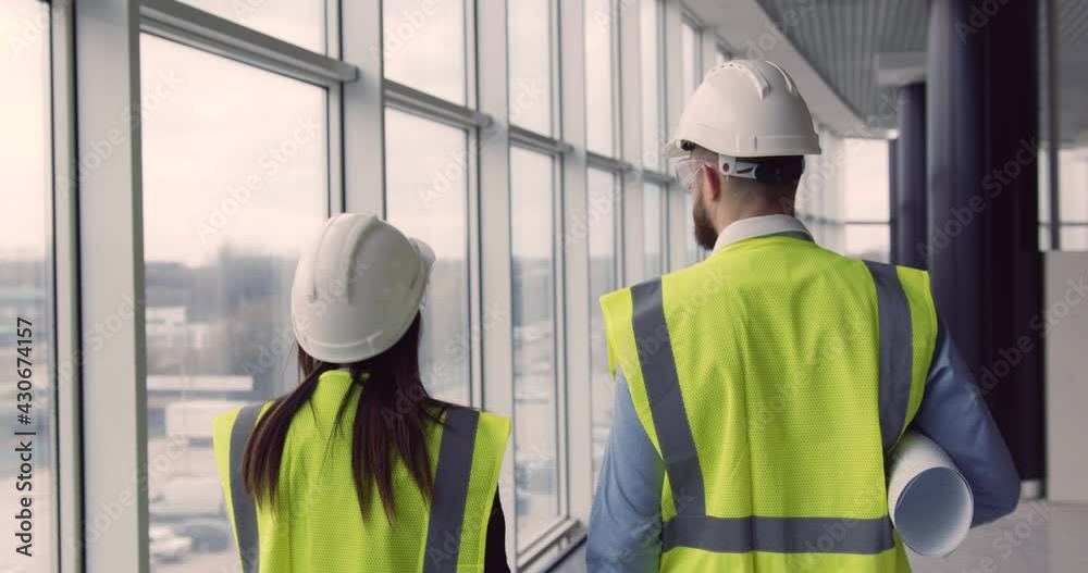 Back view of woman architect and chief male engineer walking at ...