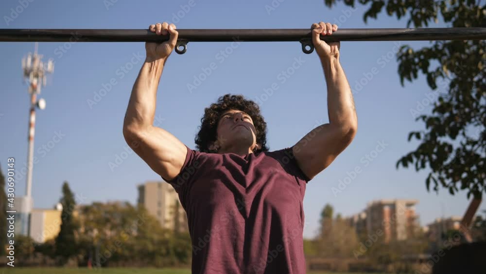 training, sport - young man trains doing pull-ups at the bar in the ...