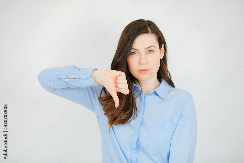 Discontent woman shows diapproval sign, keeps thumb down, expresses ...