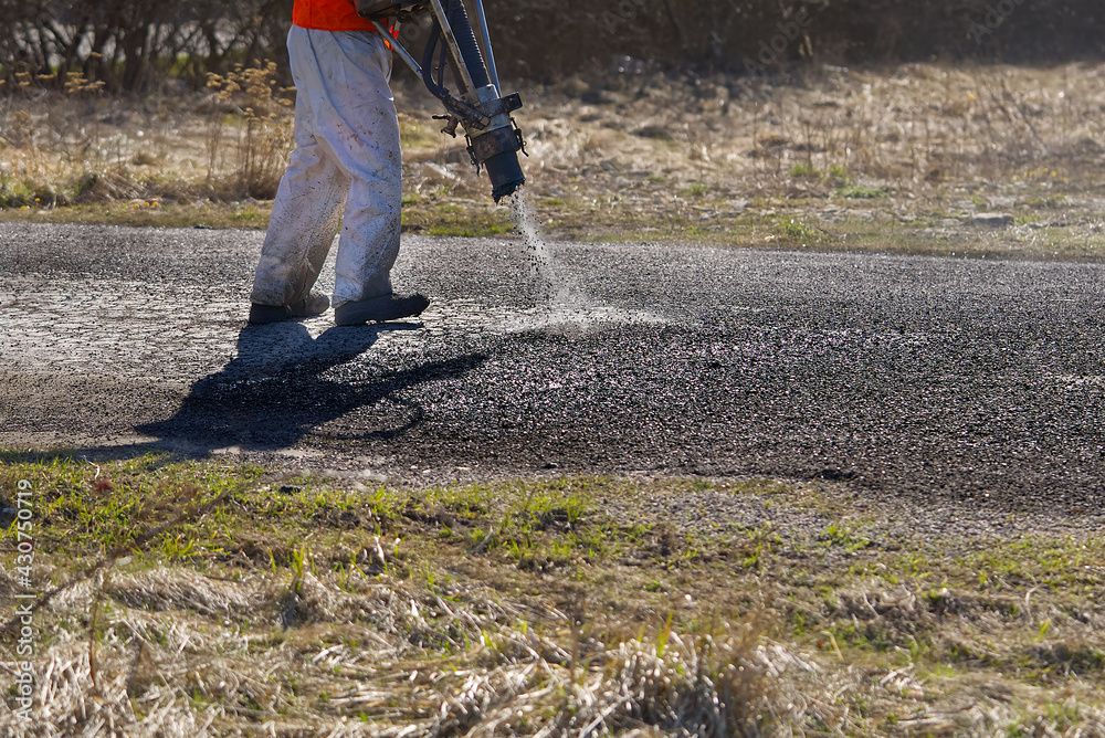 Spring fast repair of an asphalt road. Worker in uniform during fast ...