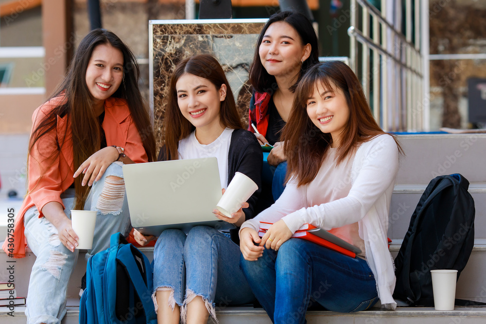 Group of four college student girls holding books and notebook computer ...