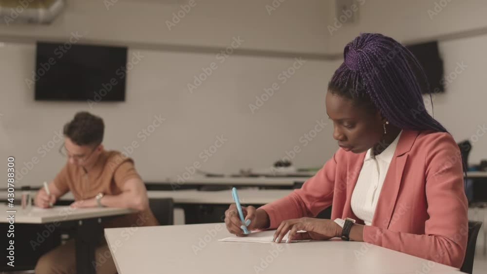 Chest-up of female African university student wearing braids, sitting ...