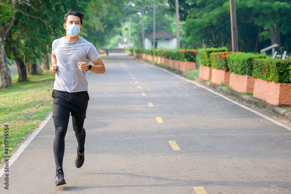 Young asian man Wear a fitness mask Run in the park Sweating from a ...