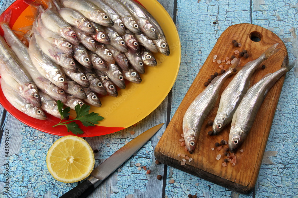 Lots of fresh smelt fish on a colorful plate and wooden background with ...