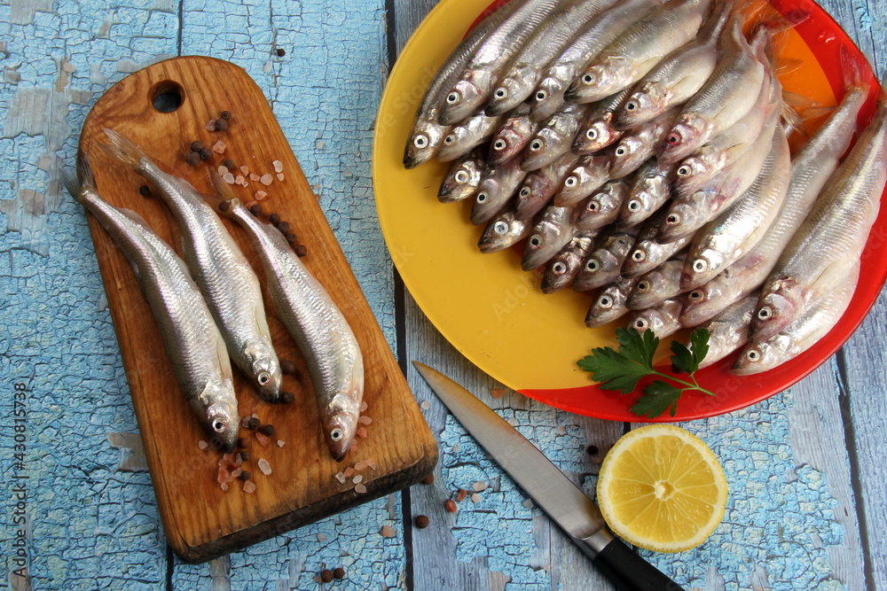 Lots of fresh smelt fish on a colorful plate and wooden background with ...