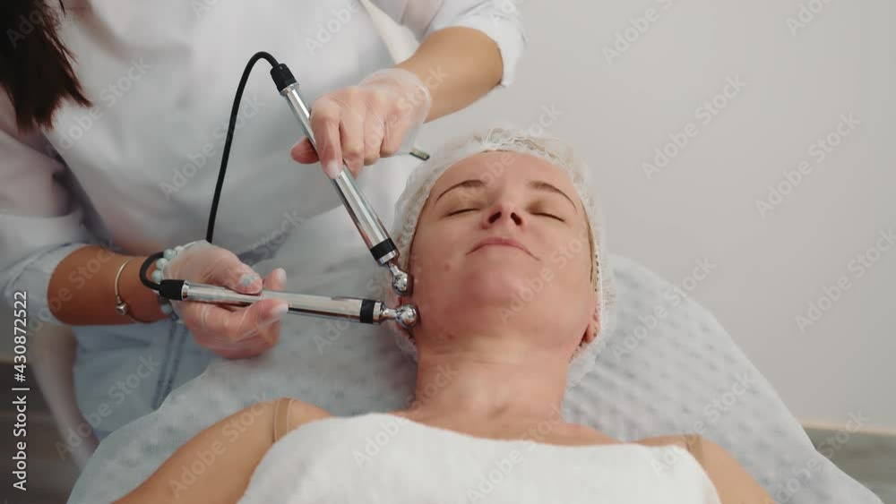 Microcurrent therapy for older women. Close-up of a beautician using ...